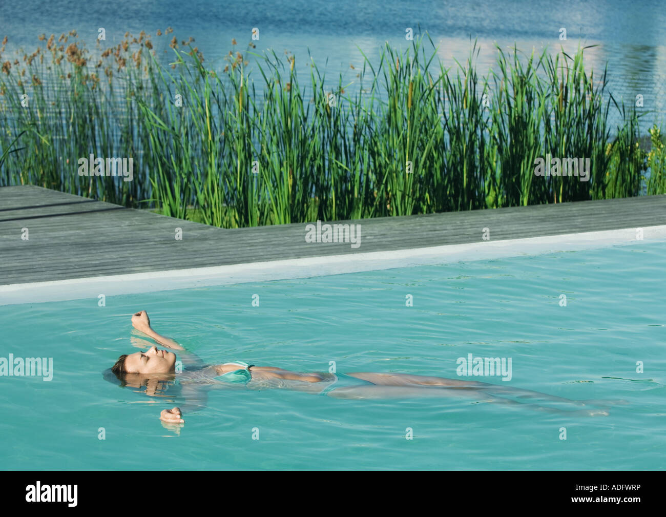 Woman floating on back in pool, full length, lake in background Stock ...