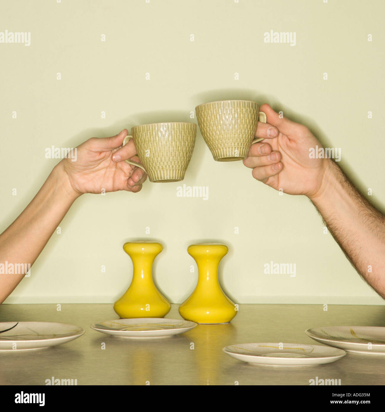 Caucasian mid adult male and female hands toasting with coffee cups ...