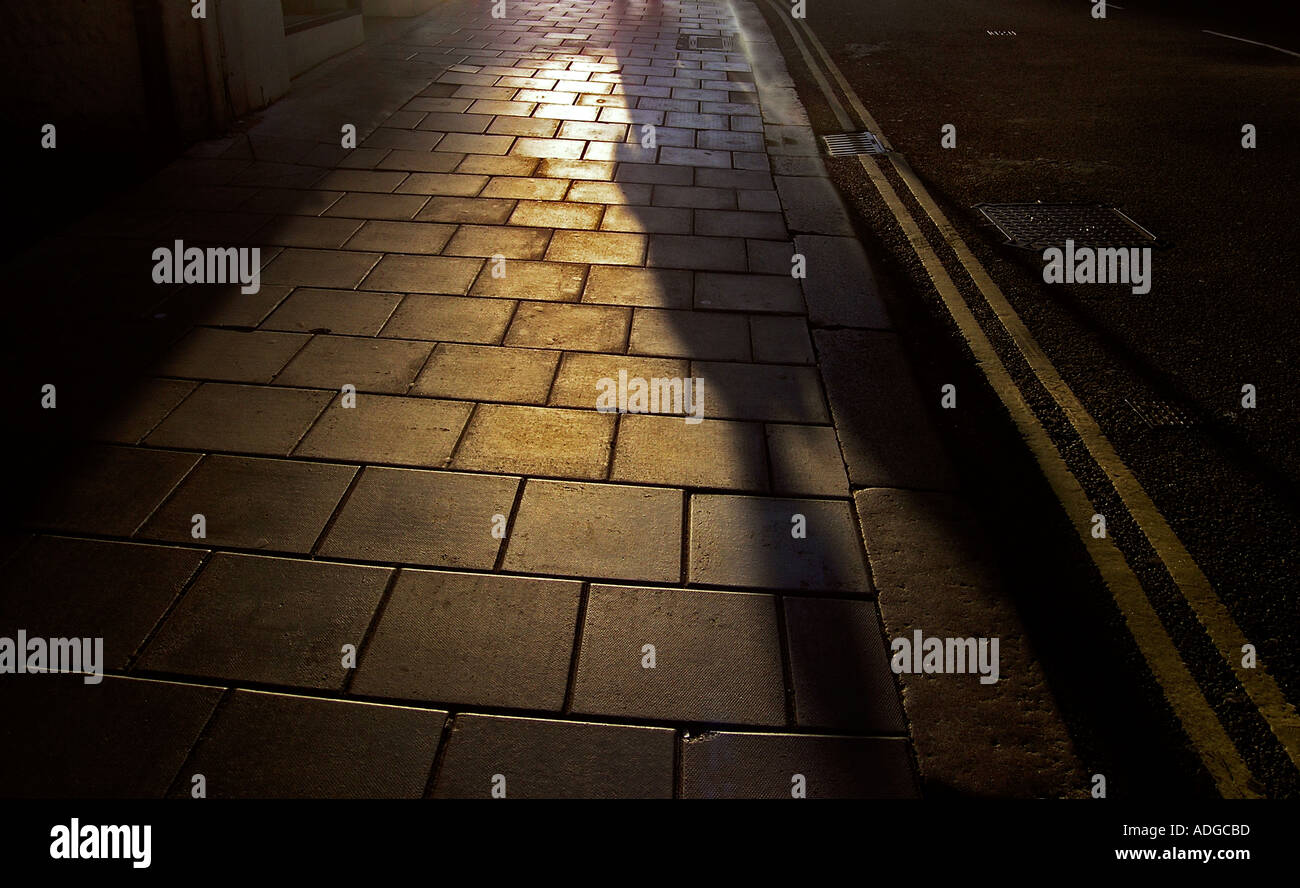 Long afternoon shadow of person walking along pavement Stock Photo - Alamy