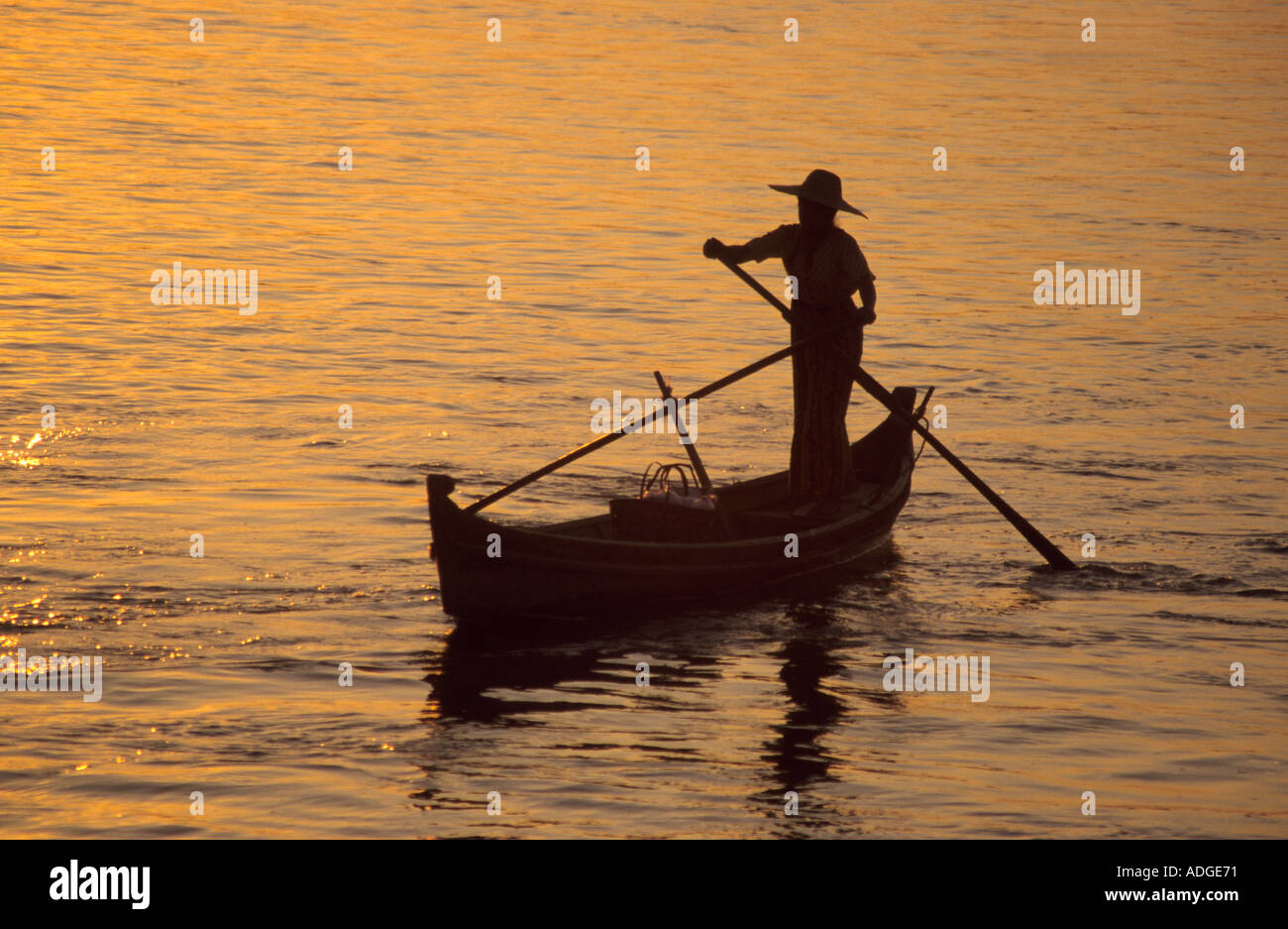 Silhouette of a Burmese boatman rowing on the Irrawaddy river at sunset ...