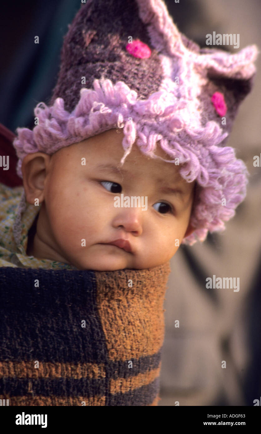 Burmese baby in pink hat being carried in a sling on her Mothers back ...