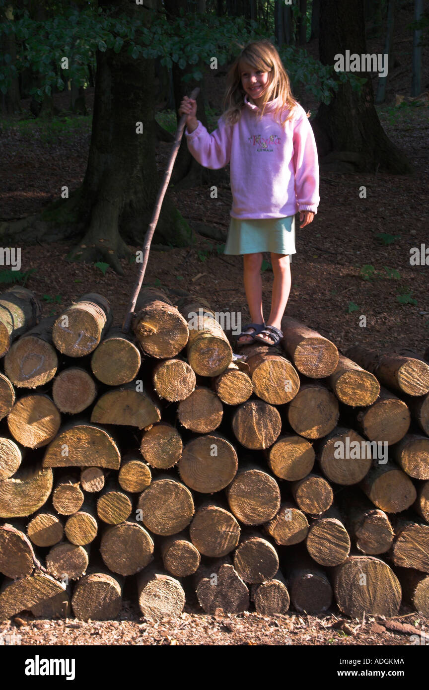 little girl standing on pile of logs Stock Photo - Alamy