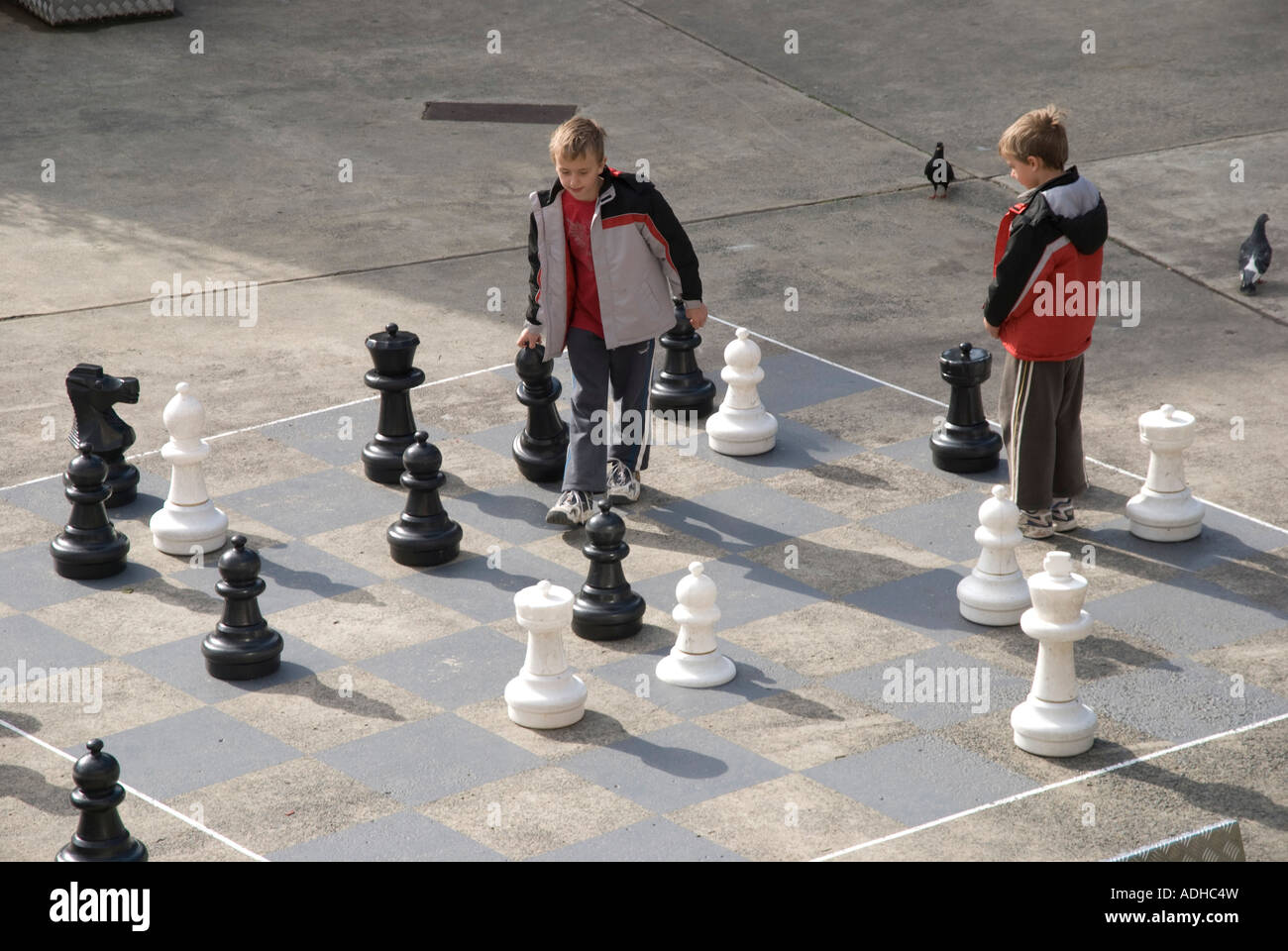 Two boys playing with a giant chess set Stock Photo - Alamy
