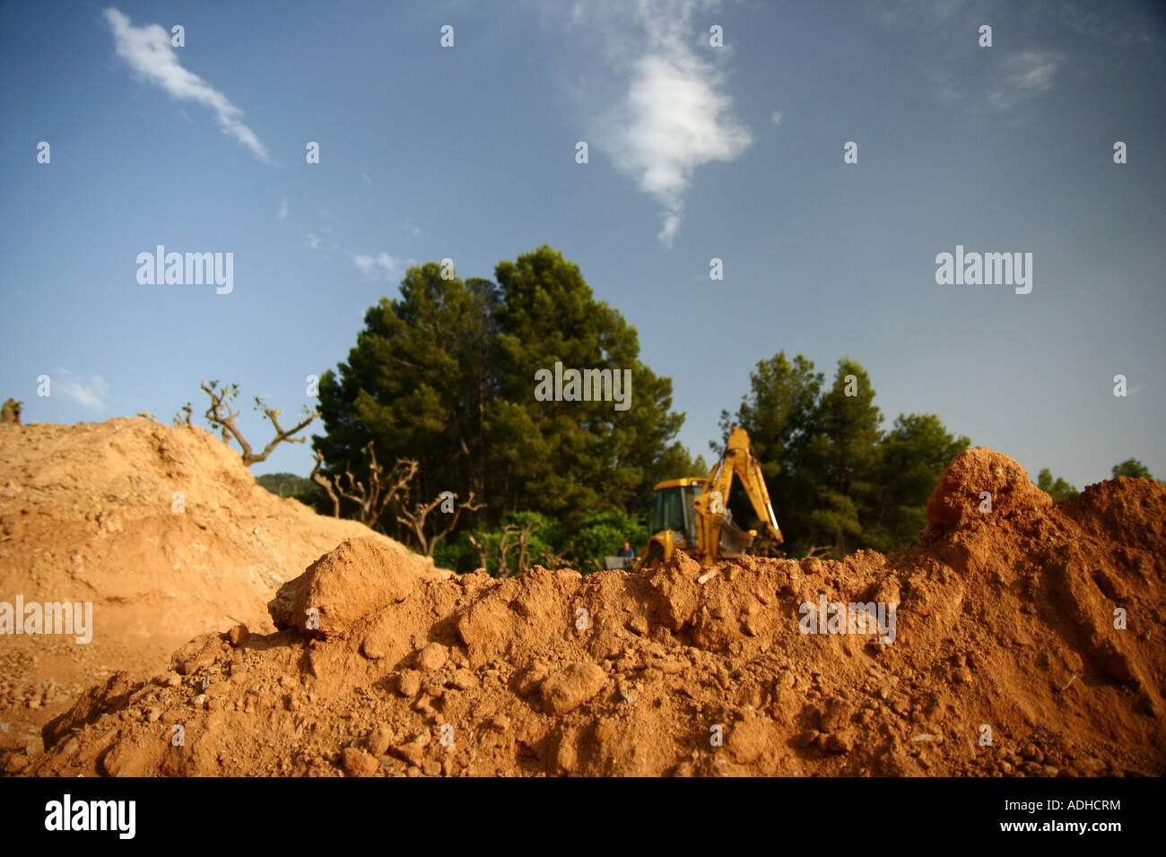 Soft ground just moved by an excavator which continues to dig in the ...