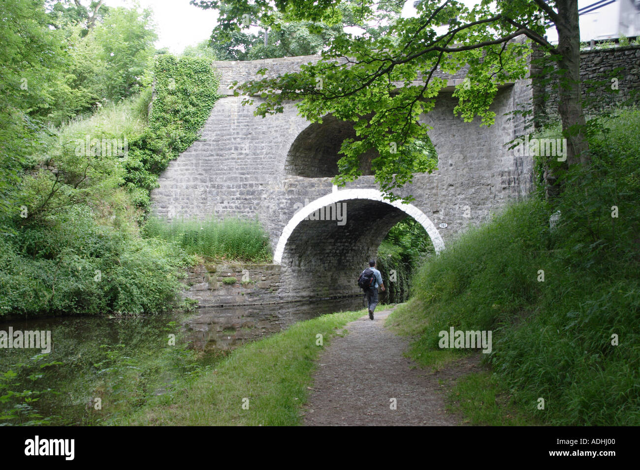 A hiker approaches a double arched bridge carrying the A59 over the ...