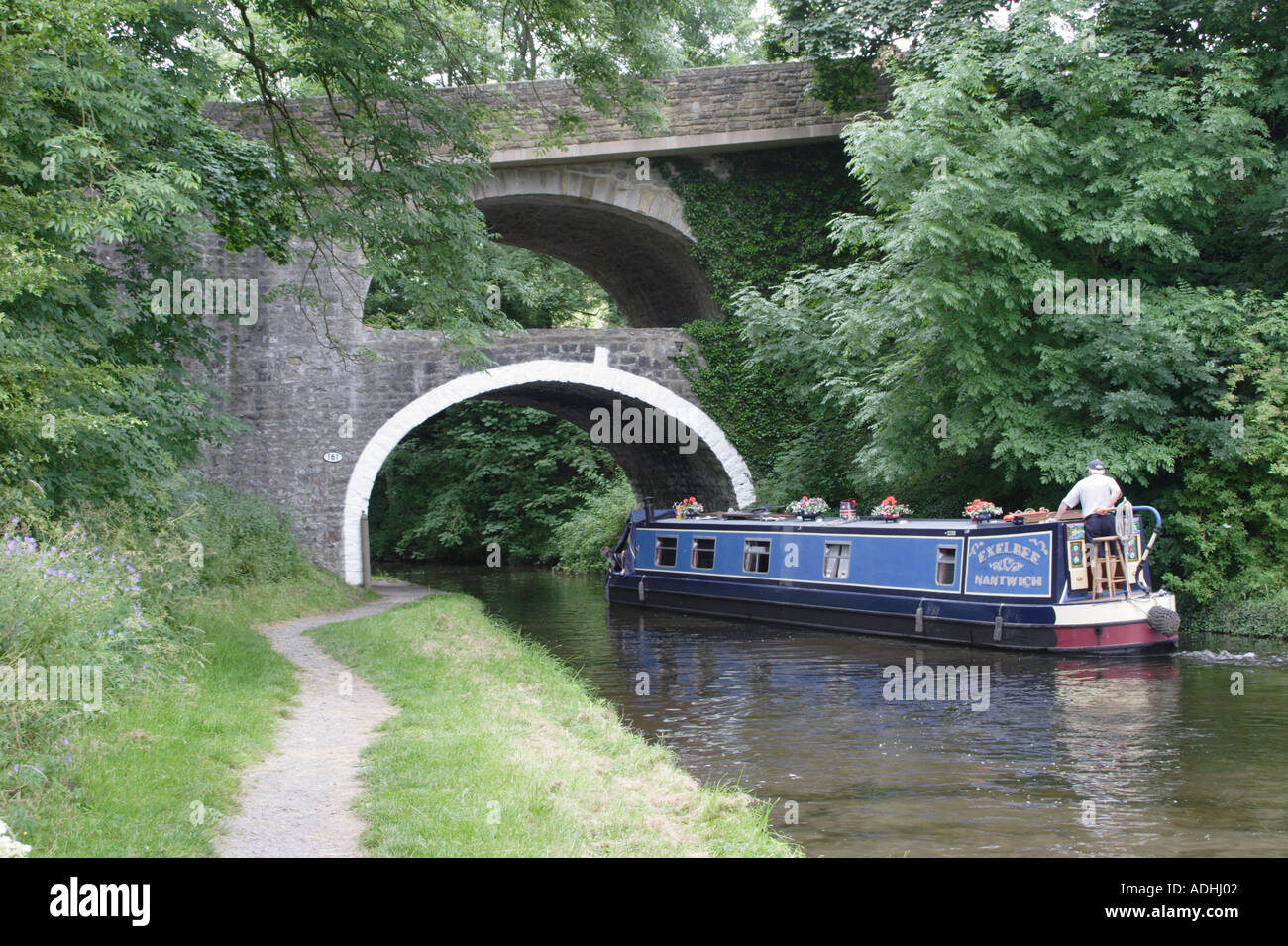 A narrowboat approaches a double arched bridge carrying the A59 over ...