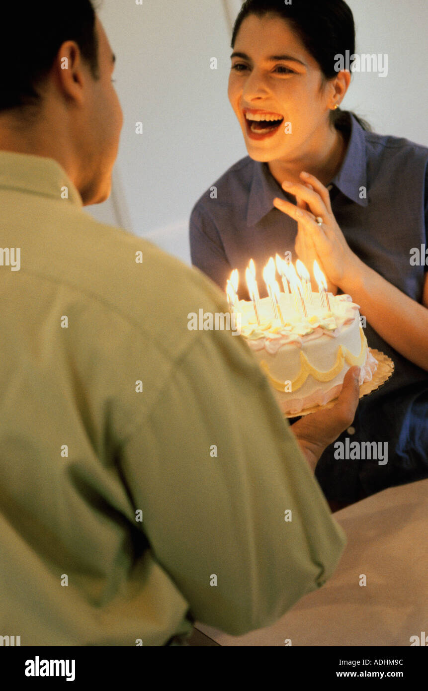 Mid adult man holding a birthday cake in front of a mid adult woman ...
