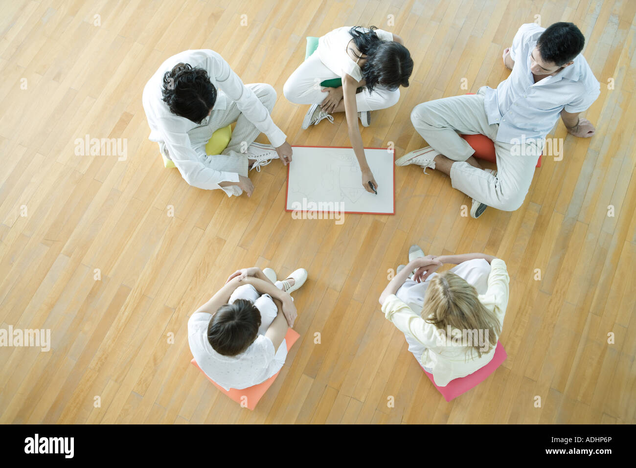 Group therapy, adults sitting in circle, one drawing on whiteboard ...