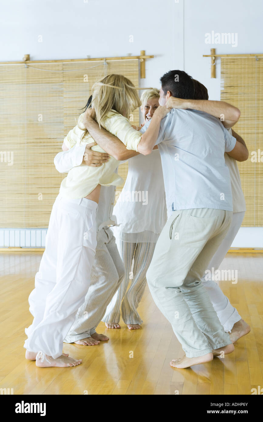Group therapy, adults standing in circle with arms around each other's ...