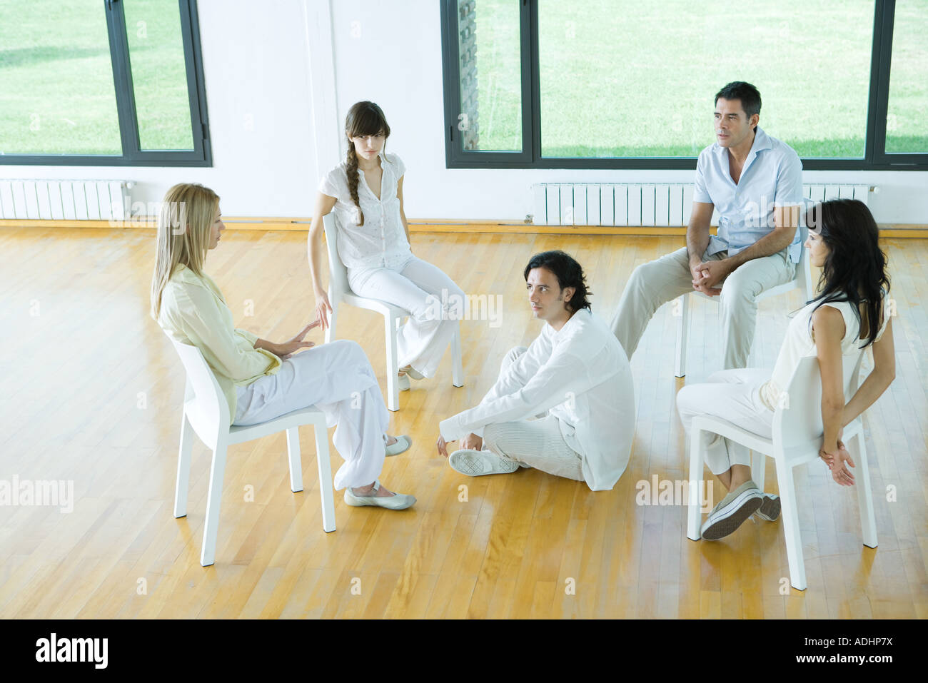 Group therapy, man sitting on floor in center of circle of adults ...