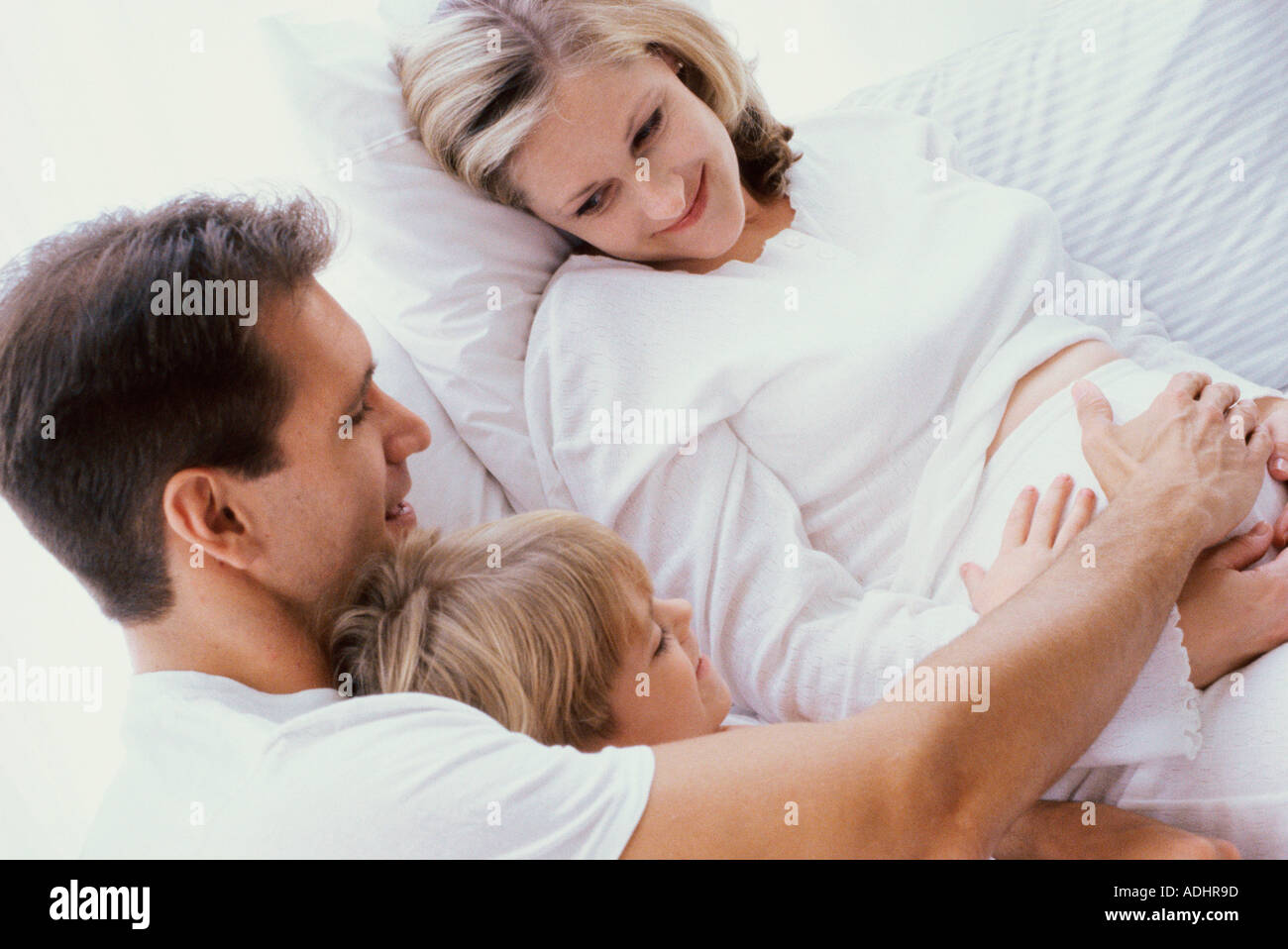 Close-up of a father and his son touching a pregnant woman' s abdomen ...