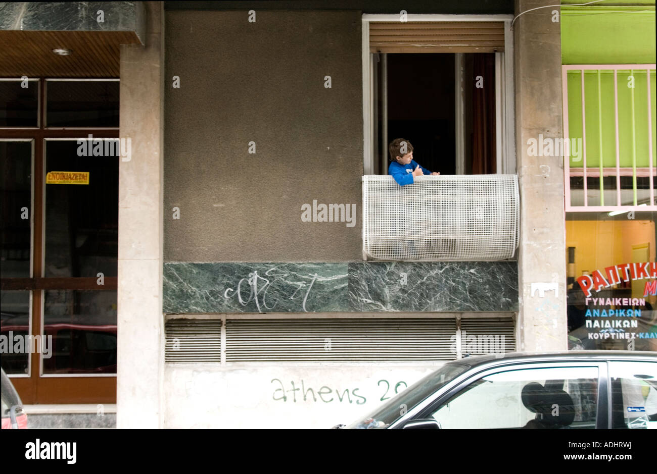 Little boy in a balcony looking on to a street in Athens Stock Photo ...