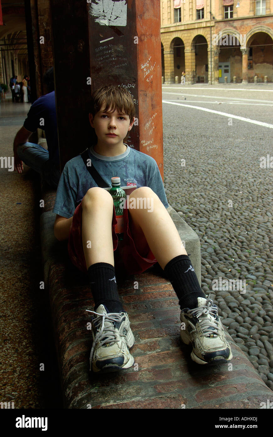 Boy 13 years old waits for parents outside a museum playing Gameboy ...