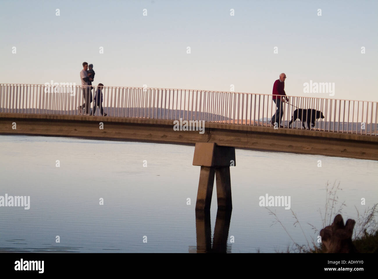 People out for a stroll crossing a footbridge over a river Stock Photo ...