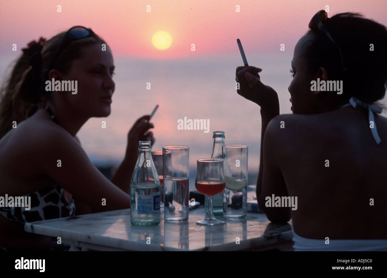 Two girls smoking and watching sunset Stock Photo - Alamy