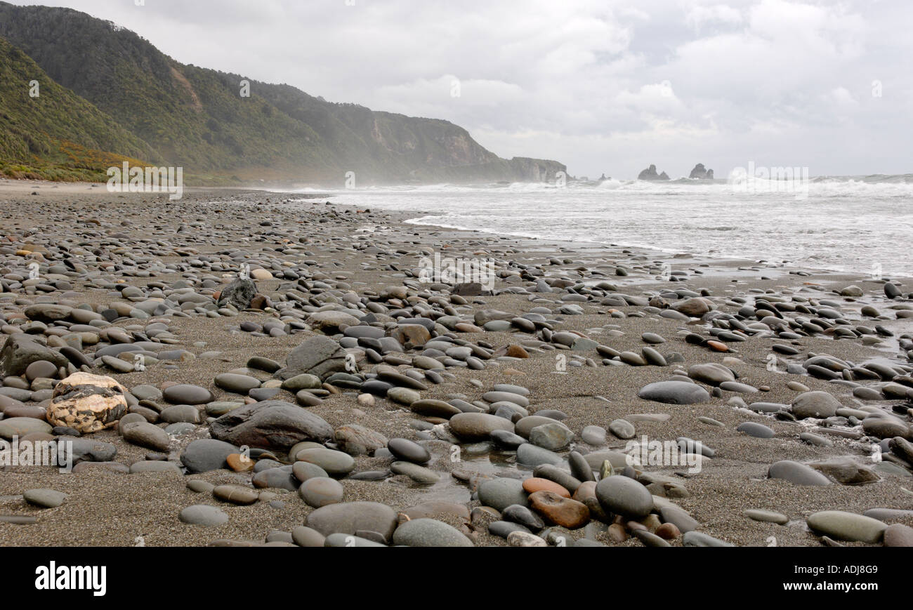 A low angled view of an unprotected rocky beach with surf rolling in ...