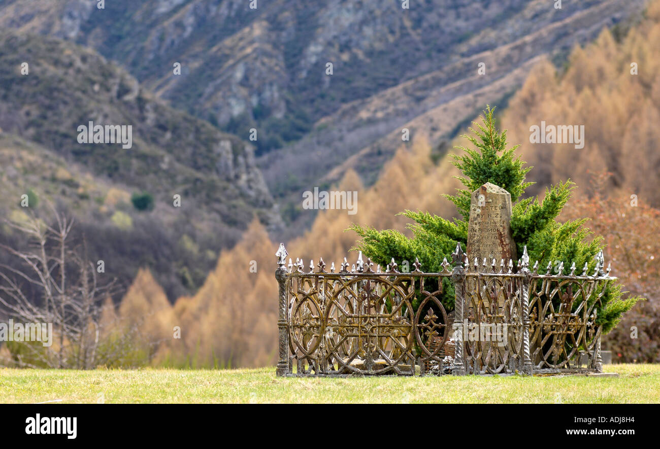 A single grave side with an ornate metal fence around it, and mountains ...