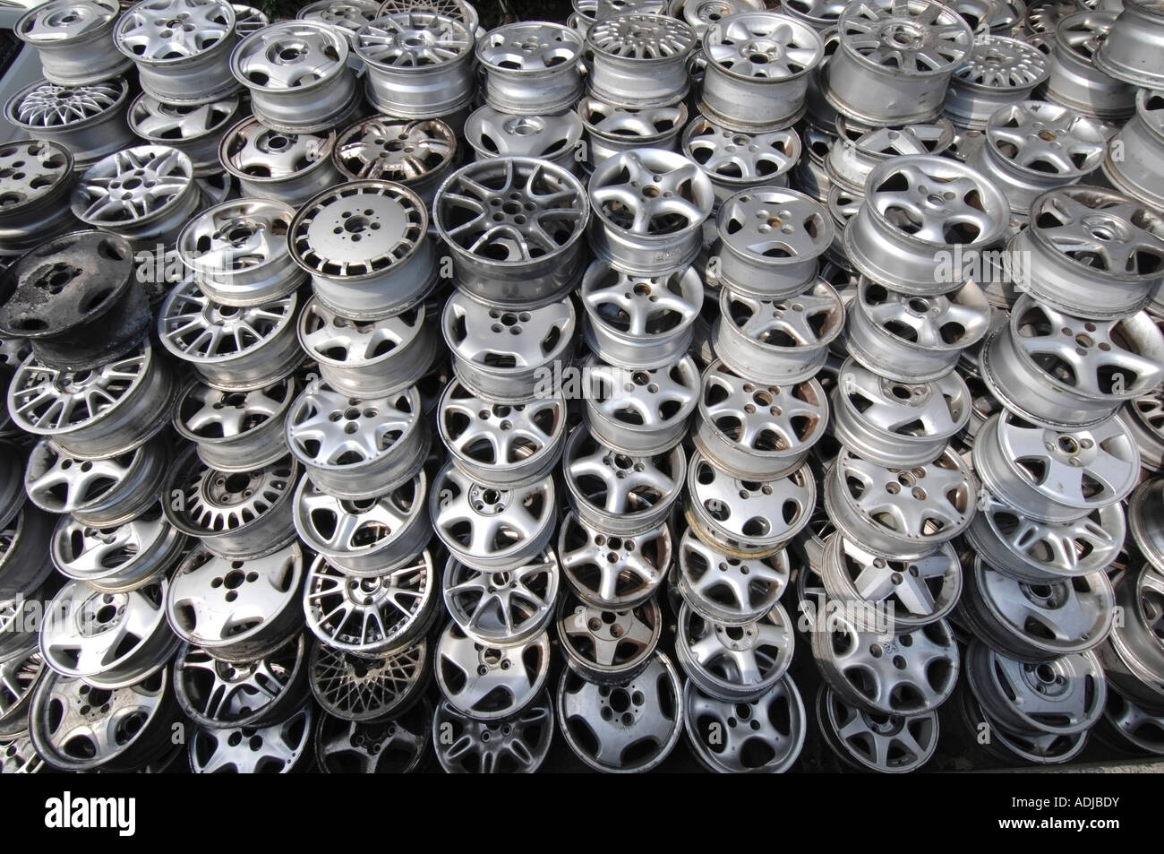 A pile of discarded second hand alloy car wheels at a scrapyard ...