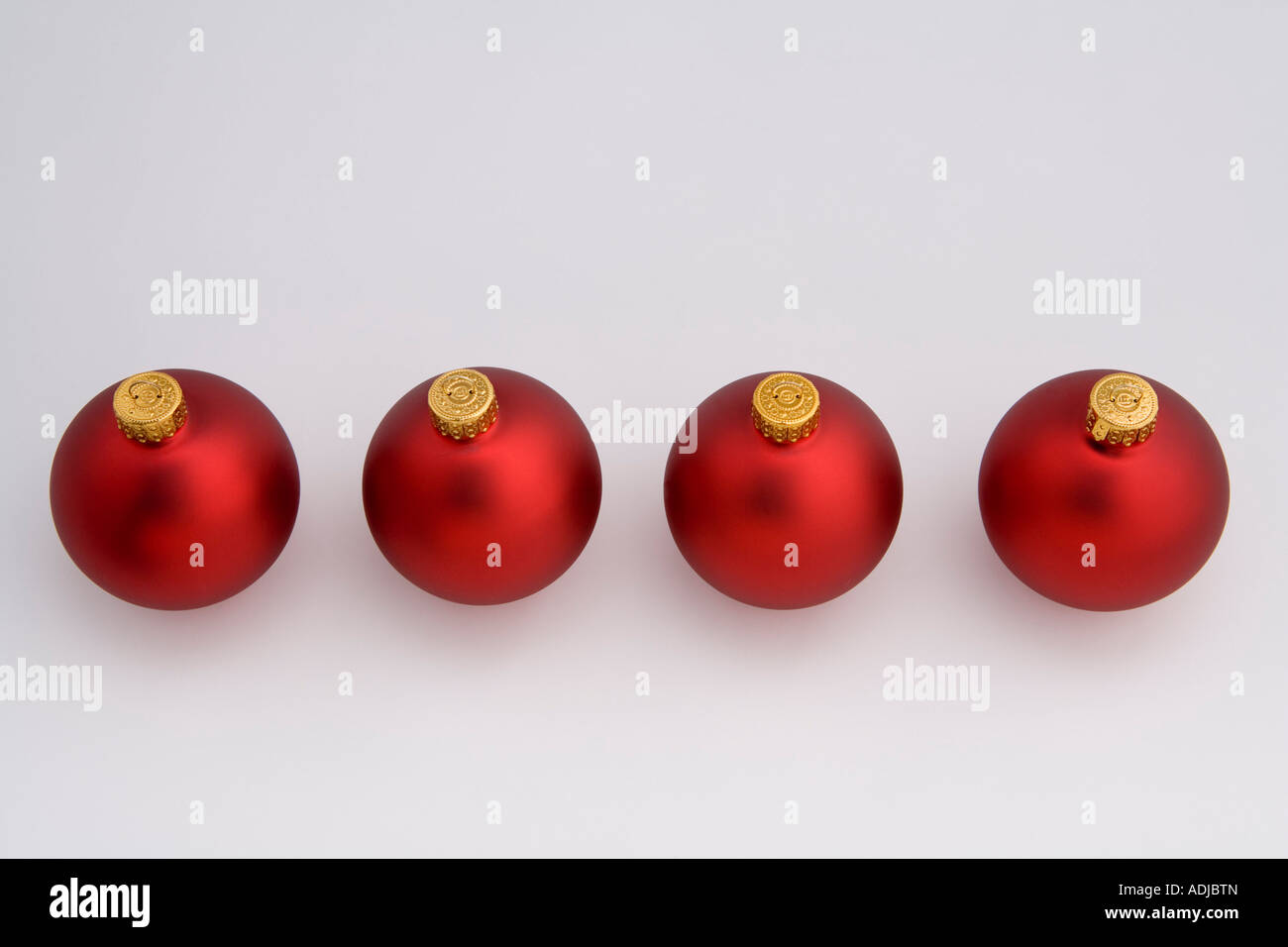 Four red Christmas balls in a diagonal line on white background studio ...