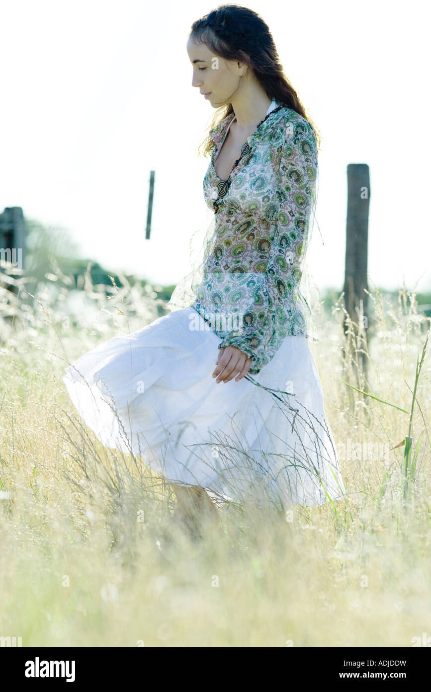 Young woman walking through field Stock Photo - Alamy