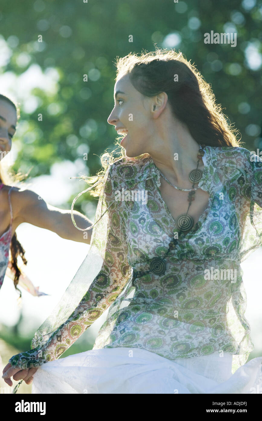 Young female friends outdoors, one looking over shoulder at the other ...