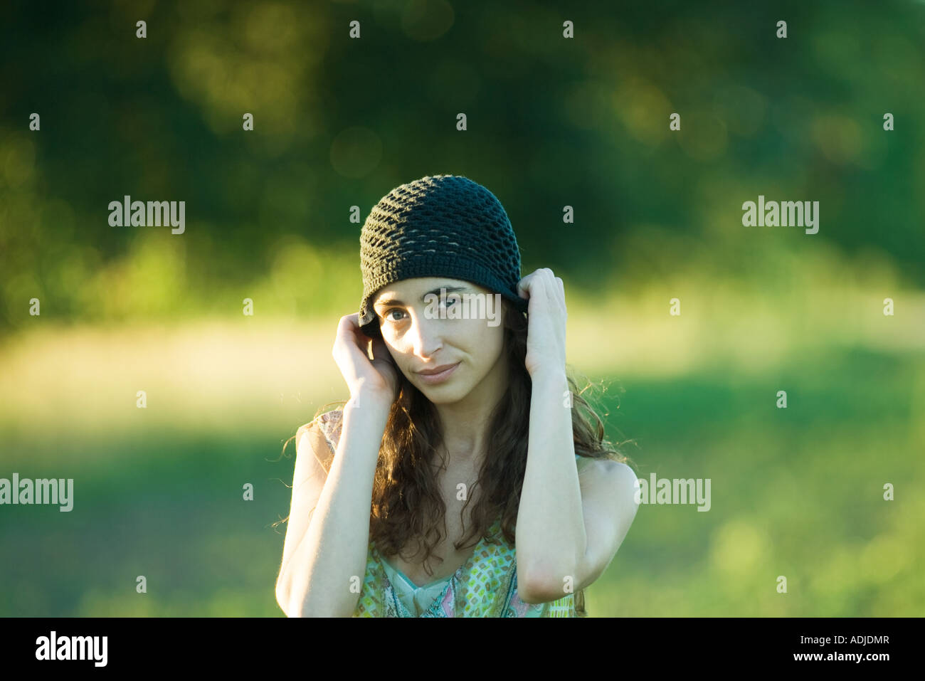 Young woman putting on hat Stock Photo - Alamy