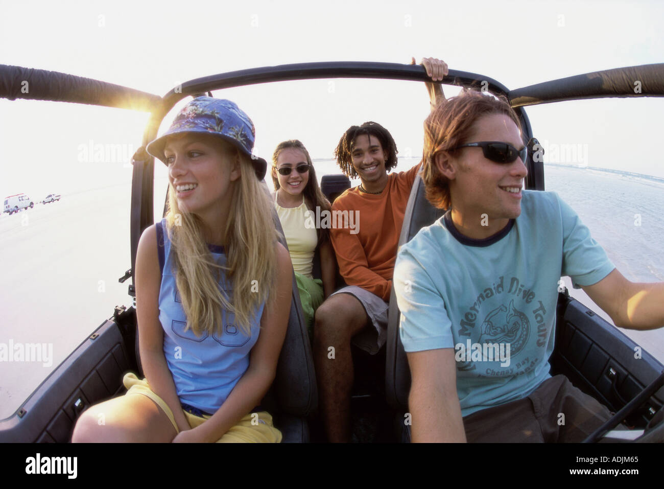 Two young couples sitting in a jeep Stock Photo - Alamy