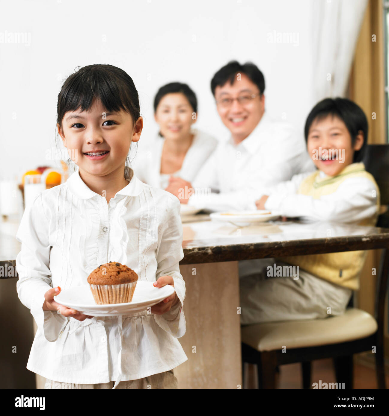 A Korean girl holding the muffin and her family are making a smile ...