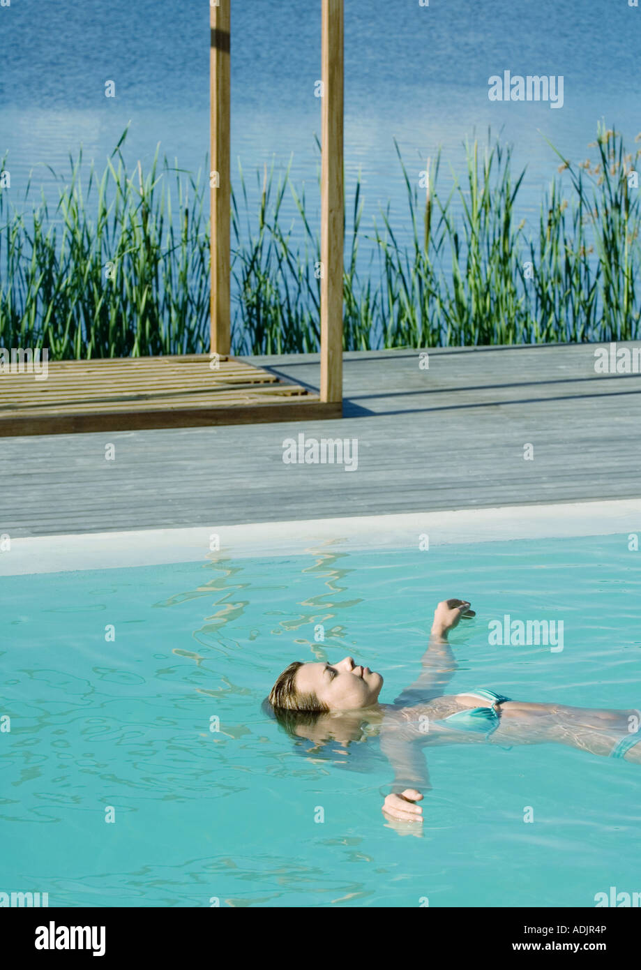 Young woman floating in pool Stock Photo - Alamy
