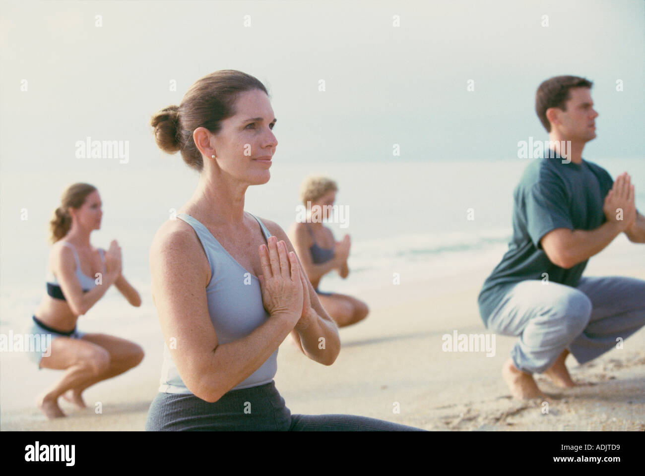 Group of people meditating on the beach Stock Photo - Alamy