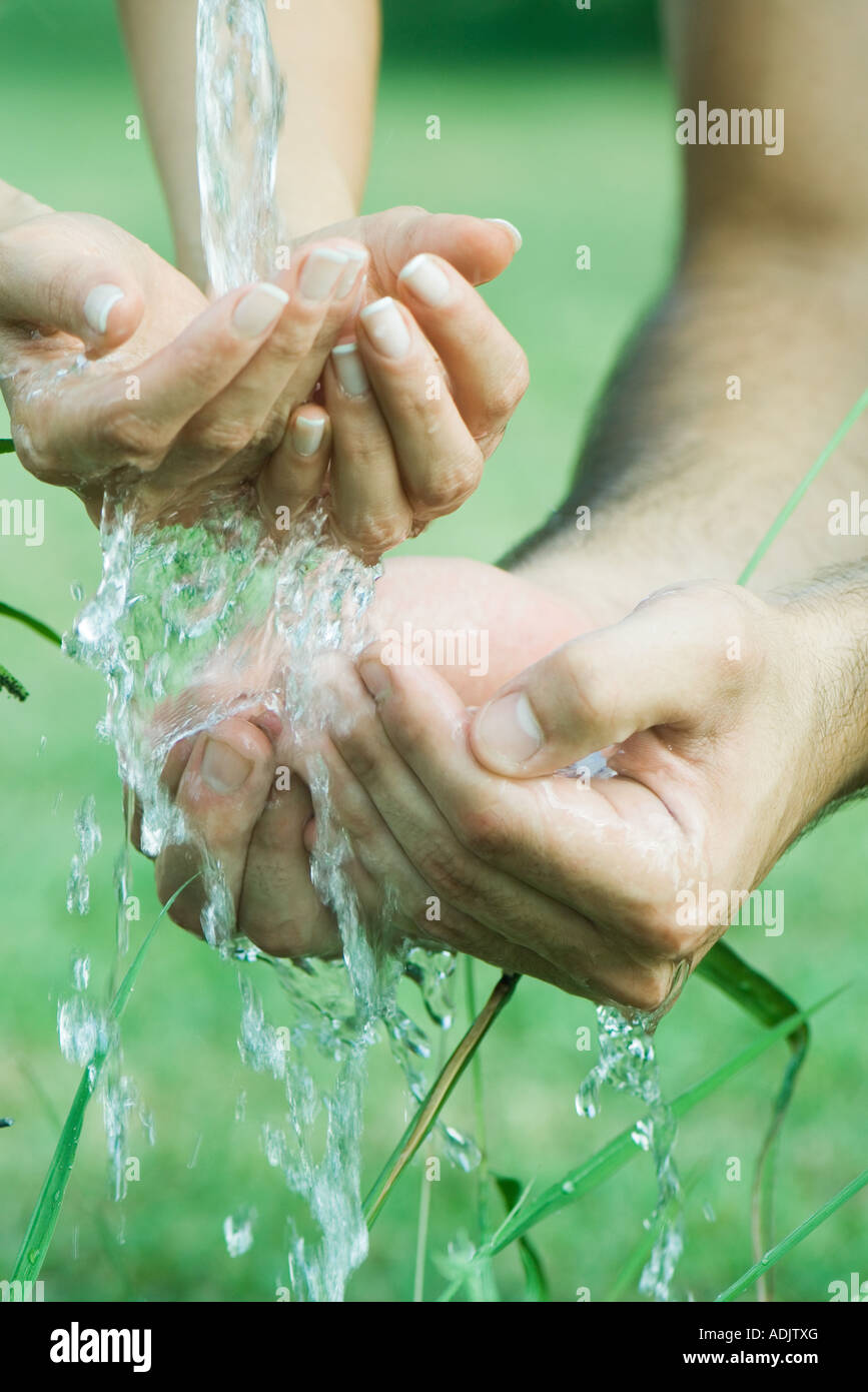 Couple cupping hands under running water Stock Photo - Alamy