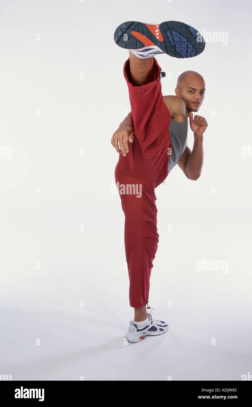 Portrait of a young man kicking with his leg Stock Photo - Alamy