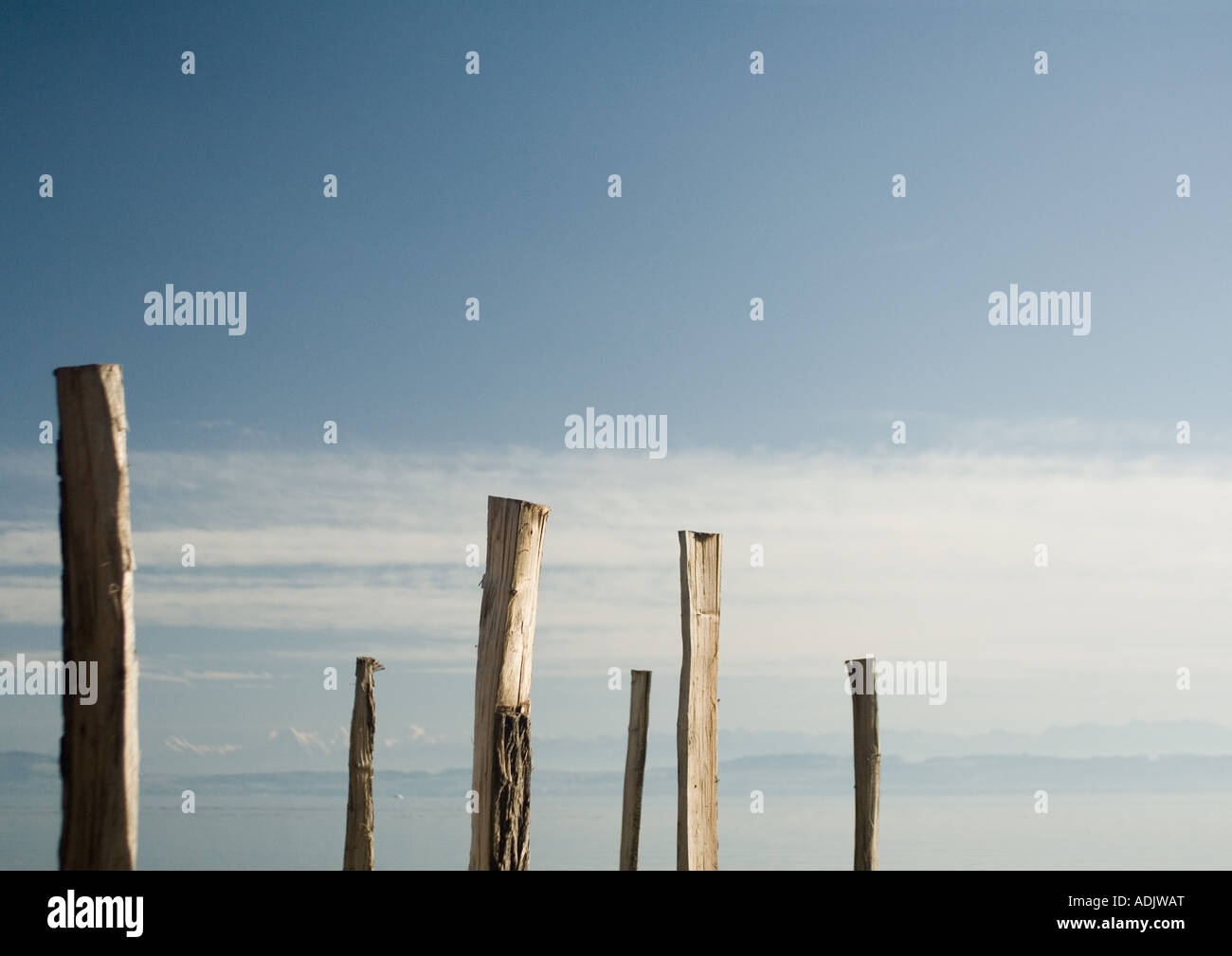Wooden posts, lake and mountains in background Stock Photo - Alamy