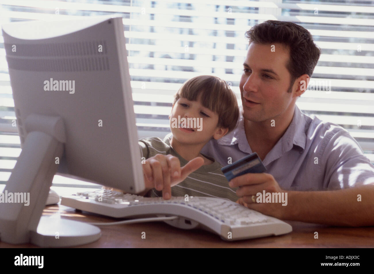 Father and his son sitting in front of a computer Stock Photo - Alamy