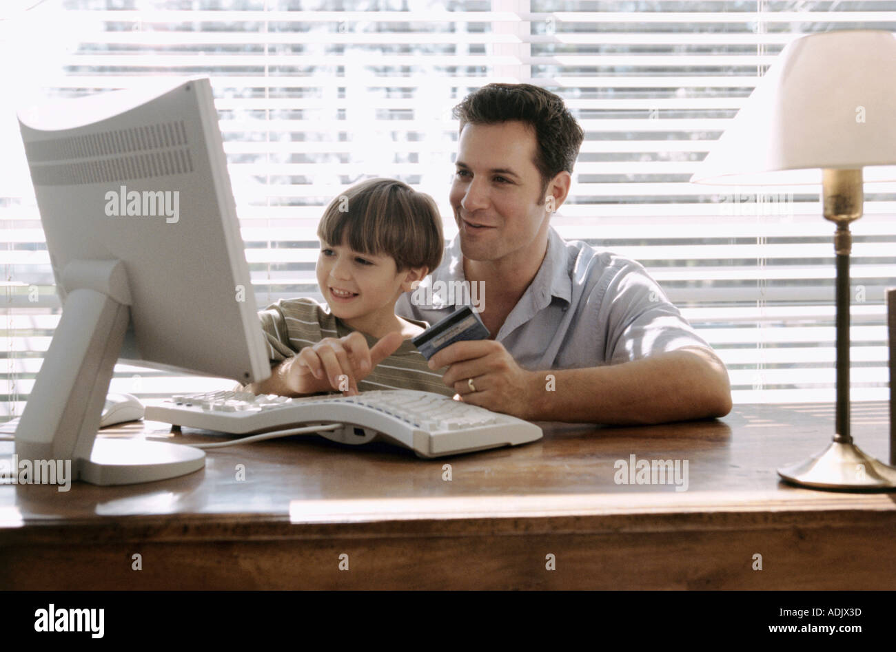 Father and his son sitting in front of a computer Stock Photo - Alamy