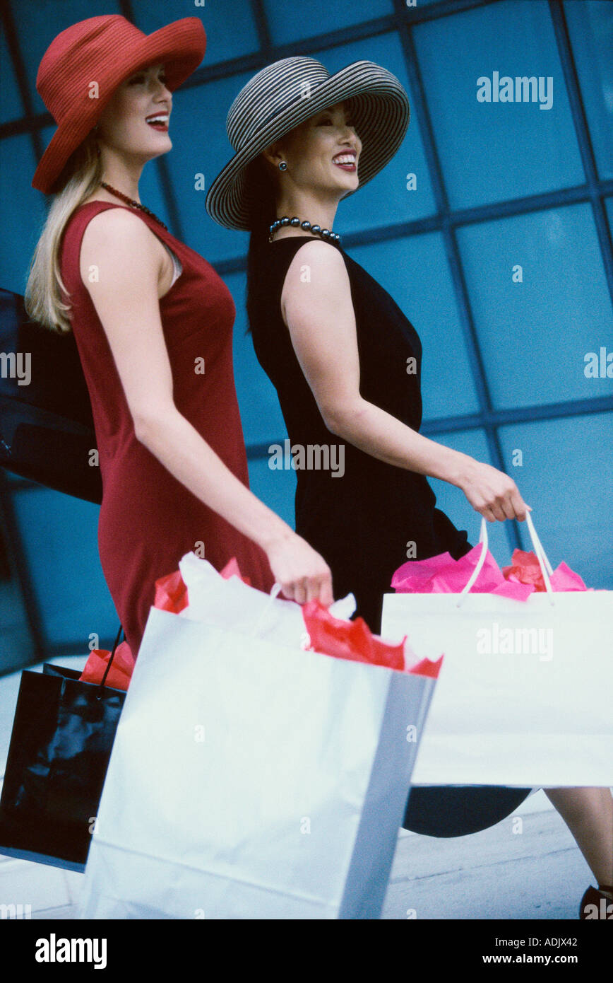 Side profile of two young women carrying shopping bags Stock Photo - Alamy