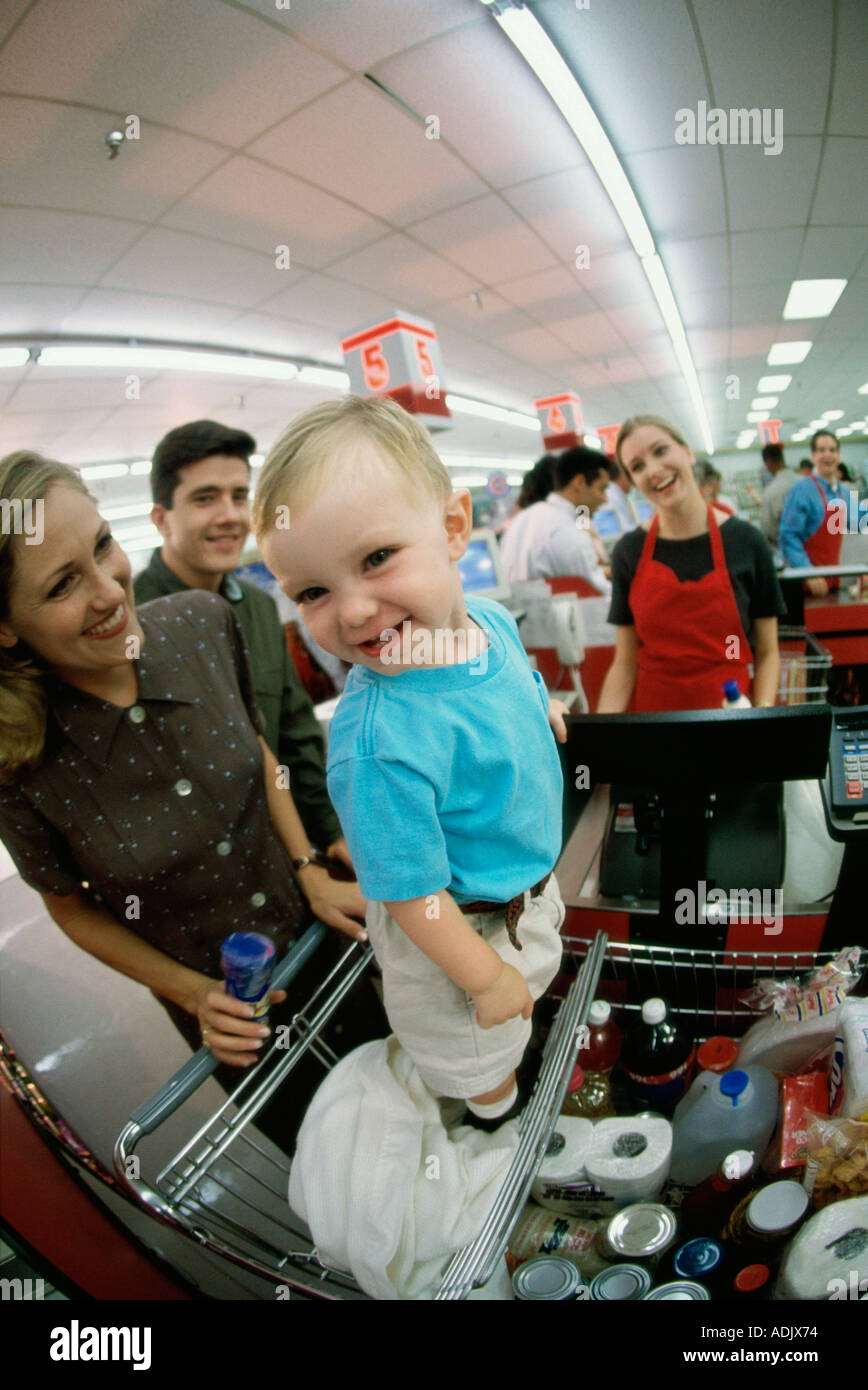 Portrait of a baby boy standing on a shopping cart in a supermarket ...