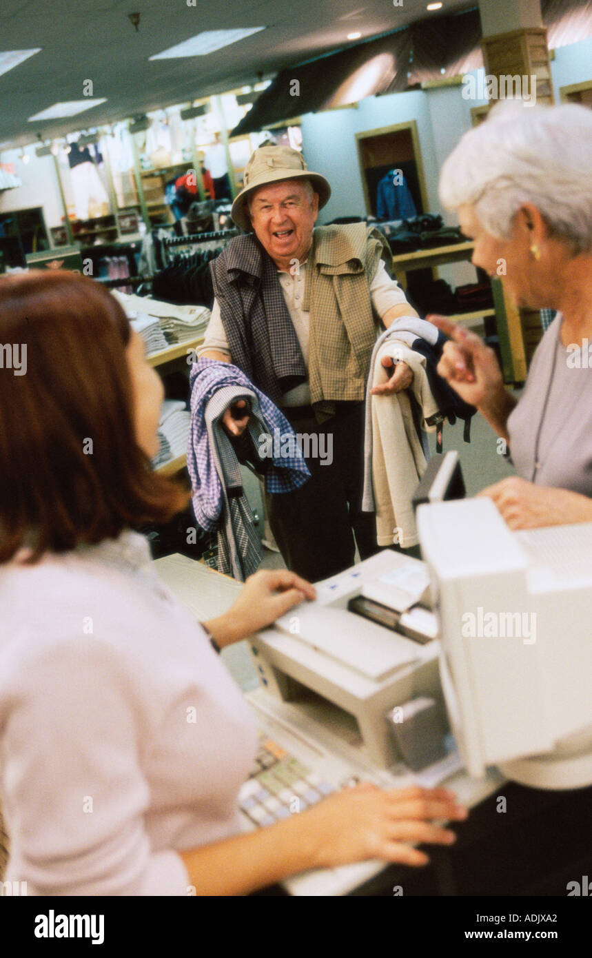Senior man carrying clothes at the checkout counter in a clothing store ...
