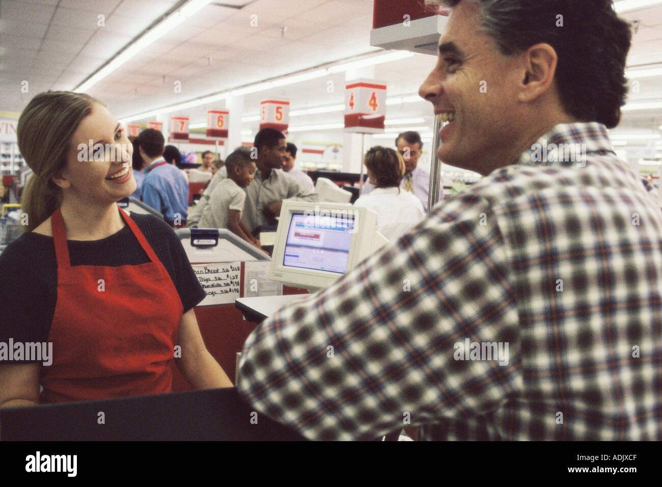 Female sales clerk talking to a customer at the checkout counter in a ...