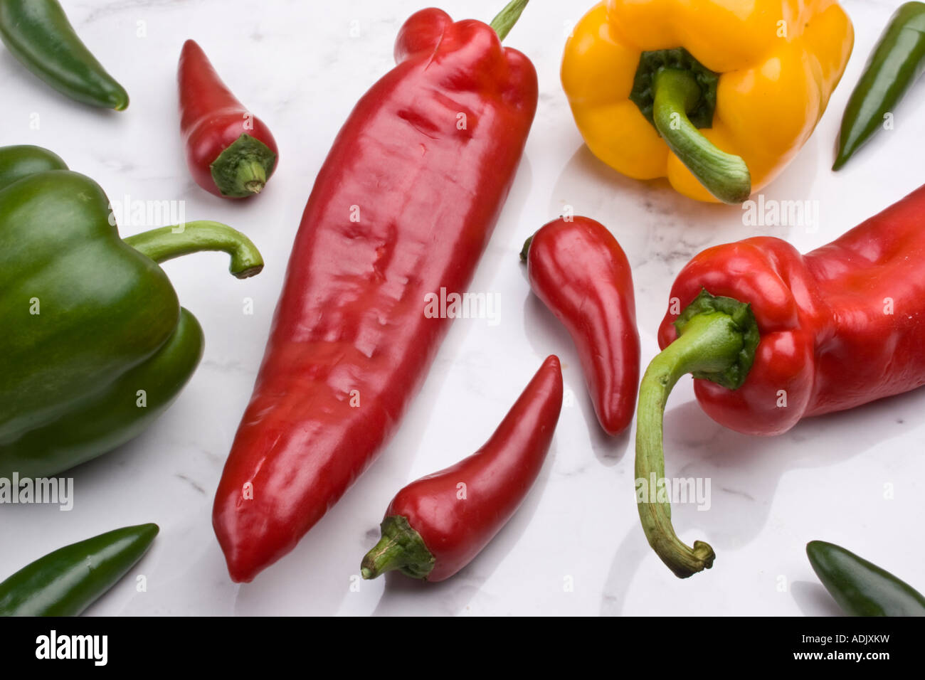 Mixture of red and green bell and chili peppers on a kitchen table ...