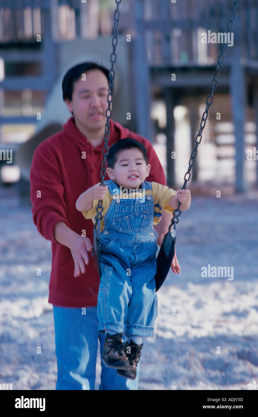 Father pushing his son on a swing Stock Photo - Alamy