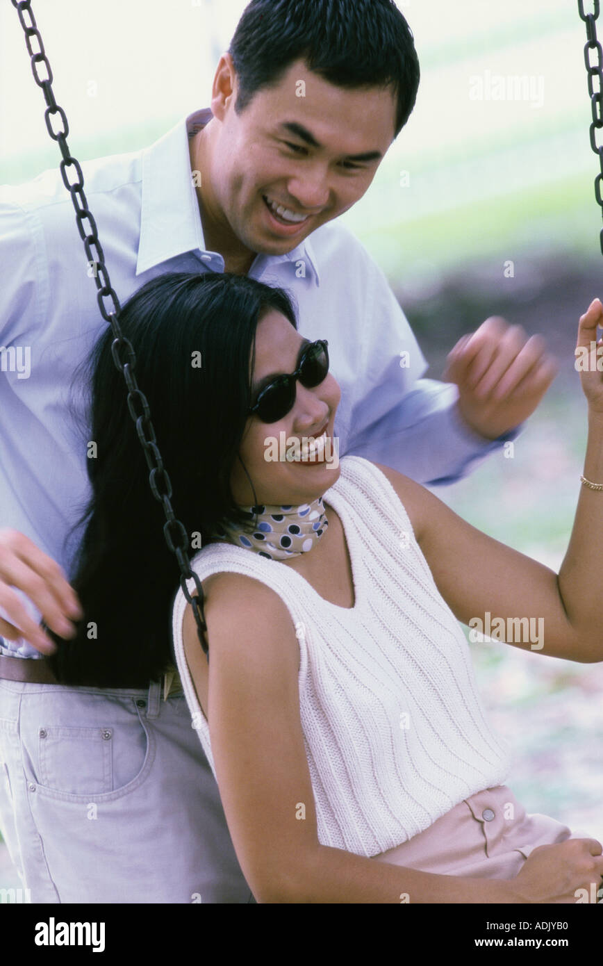 Young man pushing a young woman on a swing Stock Photo - Alamy