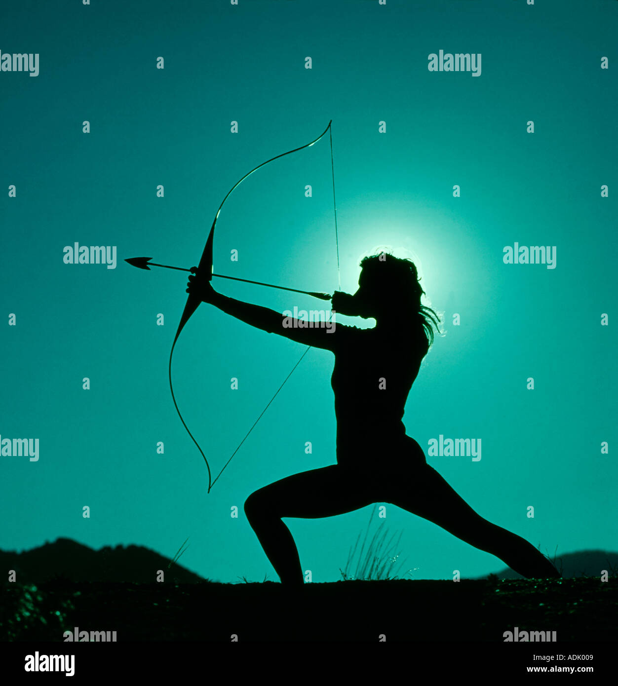 Sunset silhouette of dramatic and aggressive pose of young woman aiming ...