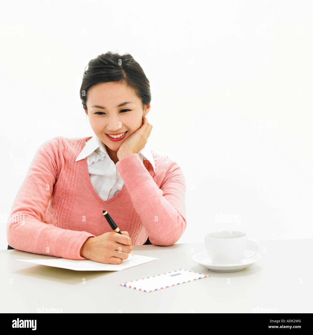 A young woman writing a letter with a smile Stock Photo - Alamy