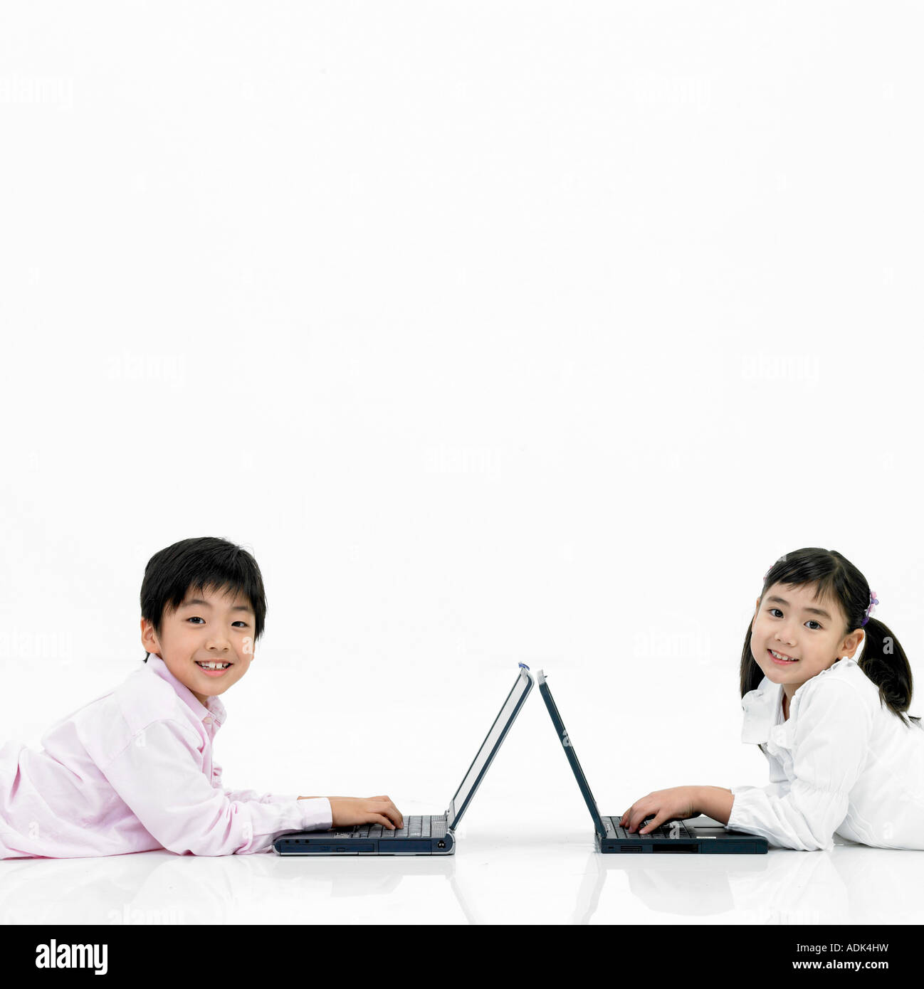 a boy and a girl prostrating with a notebook computer Stock Photo - Alamy