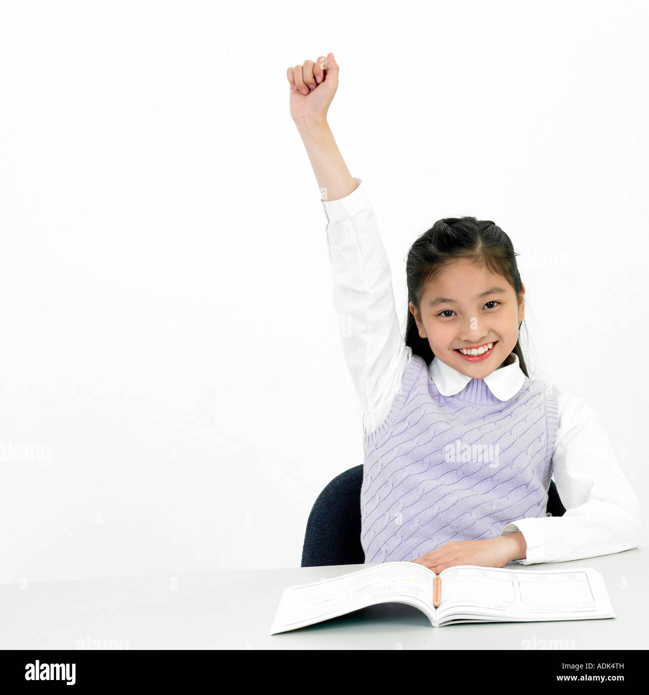a girl raising her hand with a smile in class Stock Photo - Alamy