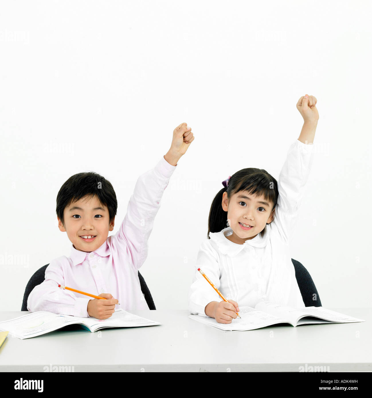 a boy and a girl raising their hands with a smile in class Stock Photo ...