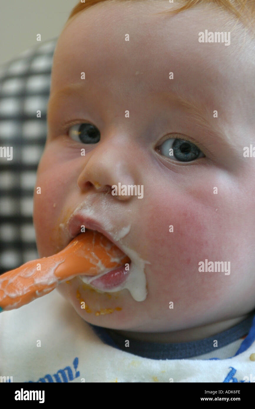 A baby feeding himself with messy face and mouth Stock Photo - Alamy