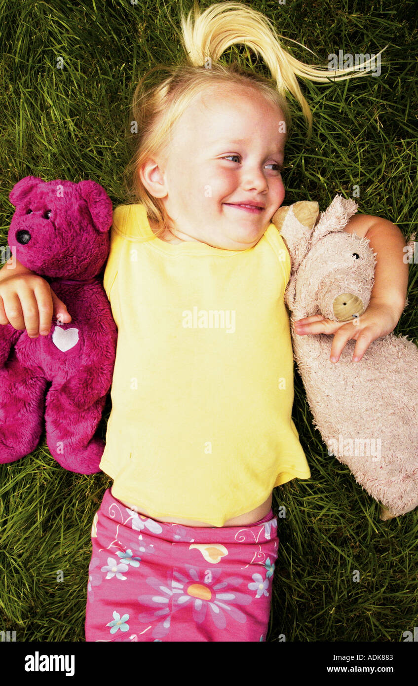 Little girl hugging her teddy bears on green grass Stock Photo - Alamy