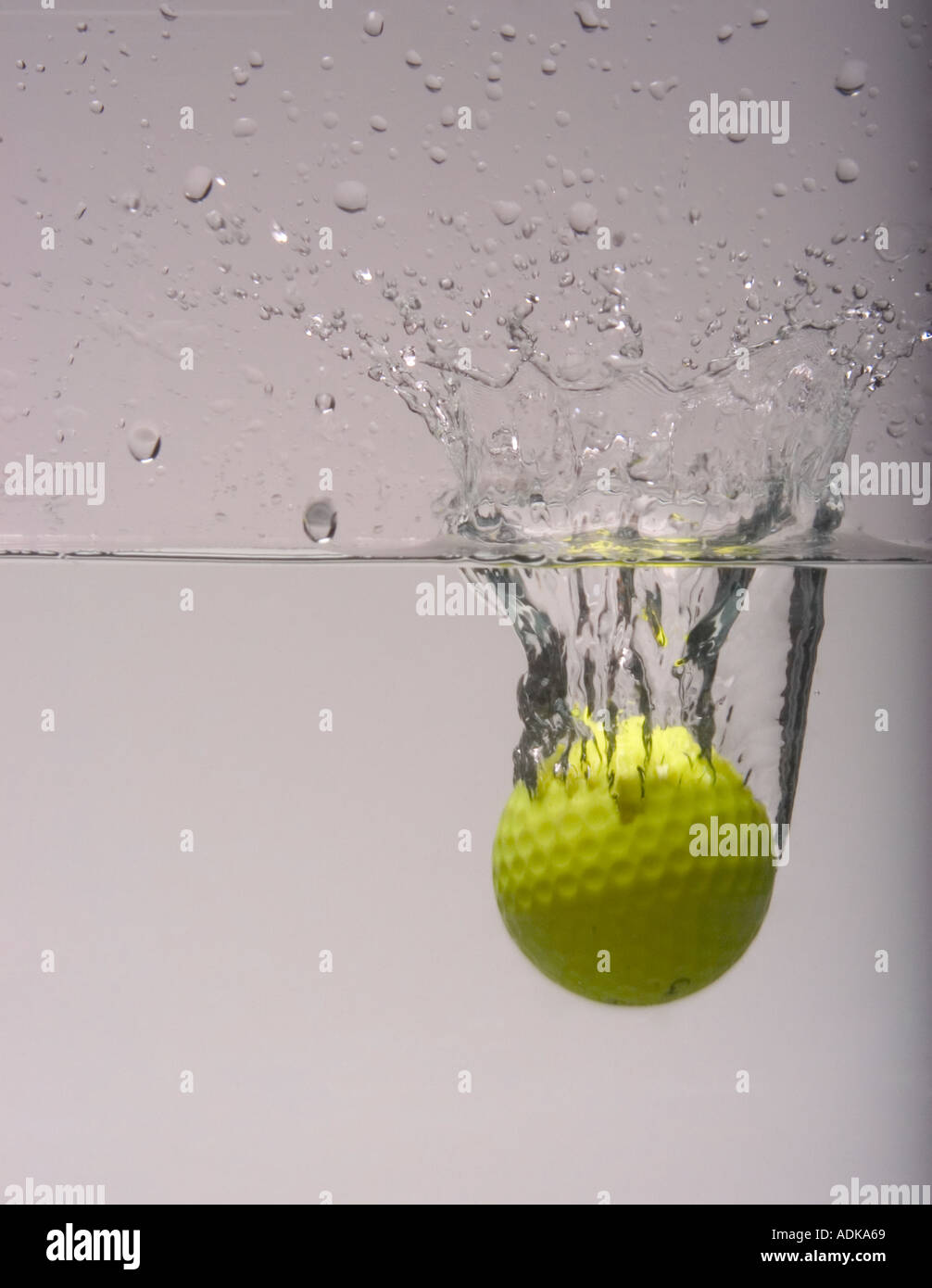 Action shot of yellow golf ball falling into water Stock Photo - Alamy